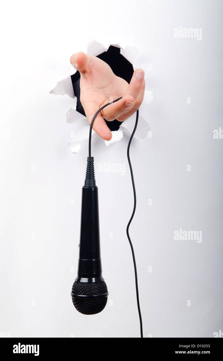 Hand holding microphone through hole in paper Stock Photo - Alamy