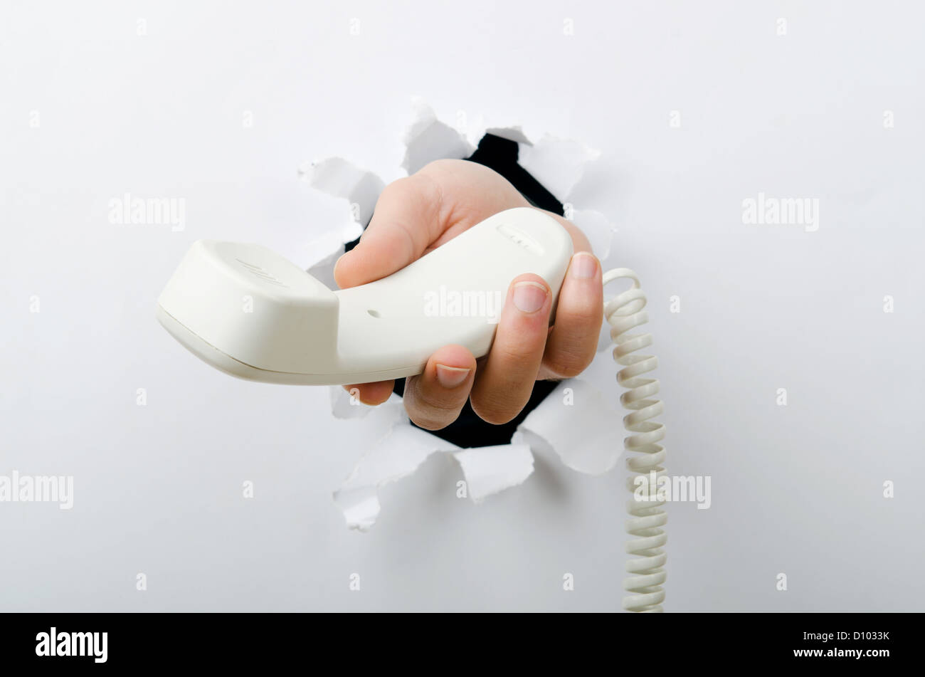 Hand holding phone through hole in paper Stock Photo - Alamy