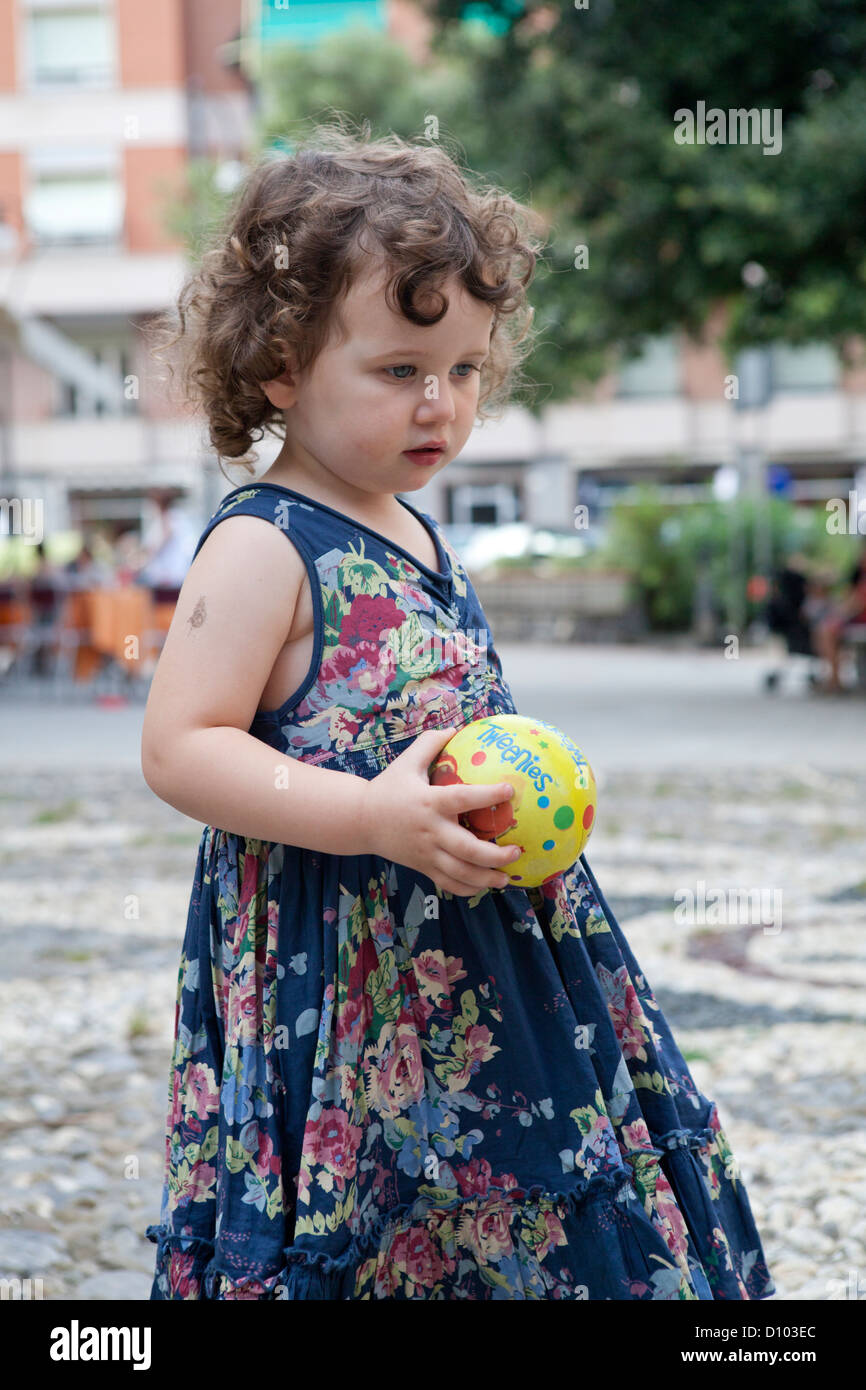Little girl holding small ball and looking sad Stock Photo - Alamy