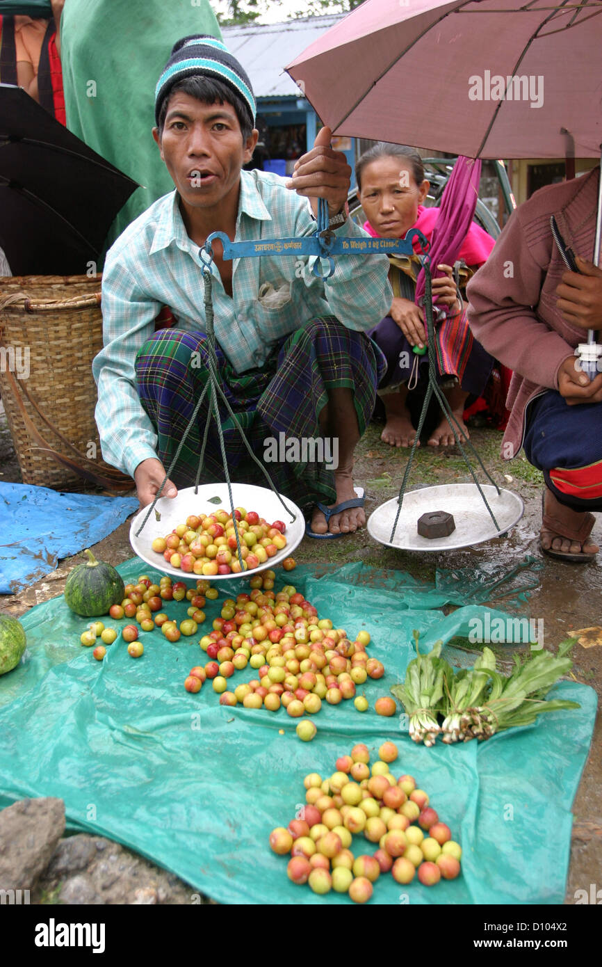 Chakma man offers a sour wild plum and vegetable in Miao market Stock ...