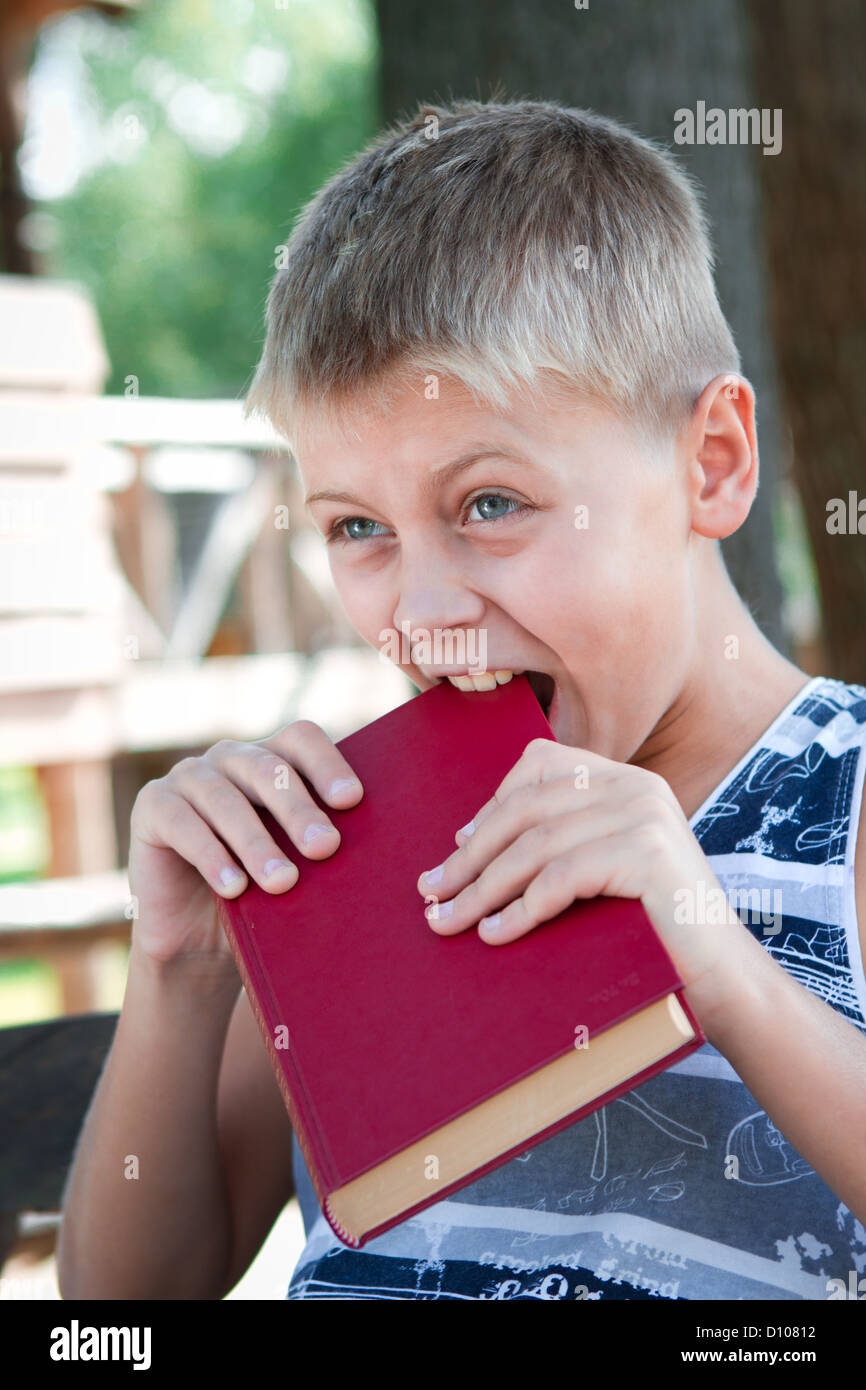 boy is biting a book on the nature Stock Photo - Alamy