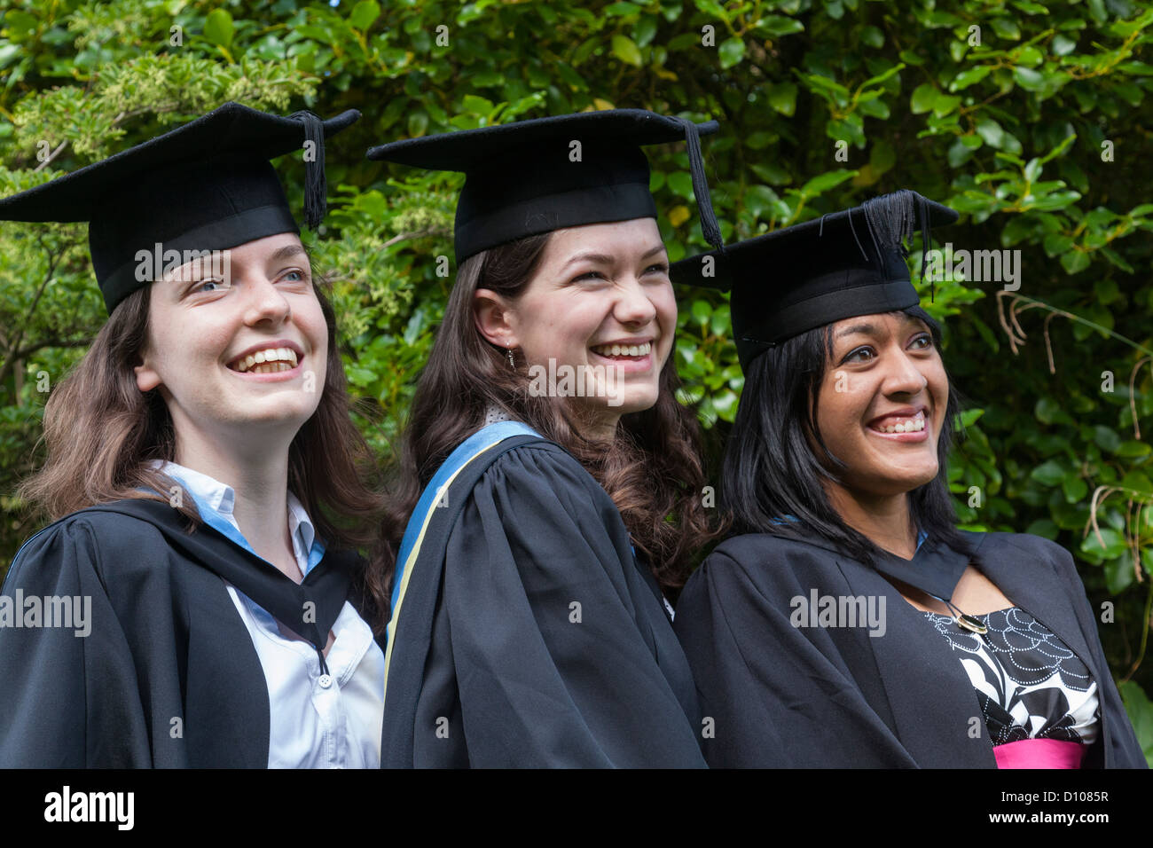 Three girls laugh whilst wearing a graduant mortar board and gown from ...