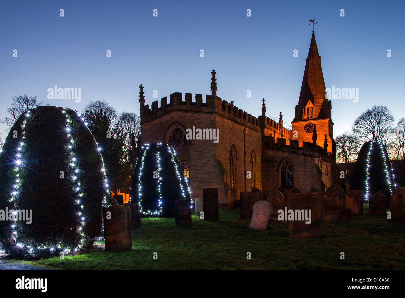 Trees covered in Christmas lights in front of St Annes church in Baslow ...