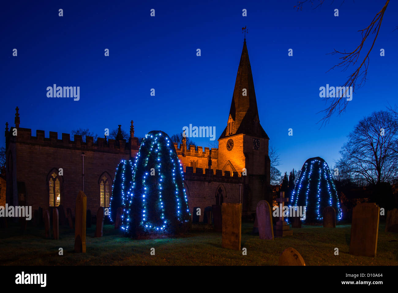 Trees covered in Christmas lights in front of St Annes church in Baslow ...