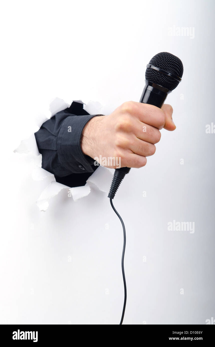 Hand holding microphone through hole in paper Stock Photo - Alamy