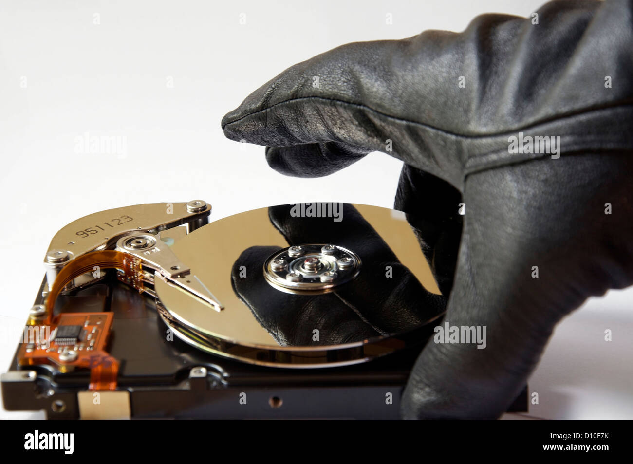 Depiction of the concept of data theft, opened harddisk and gloved hand ...