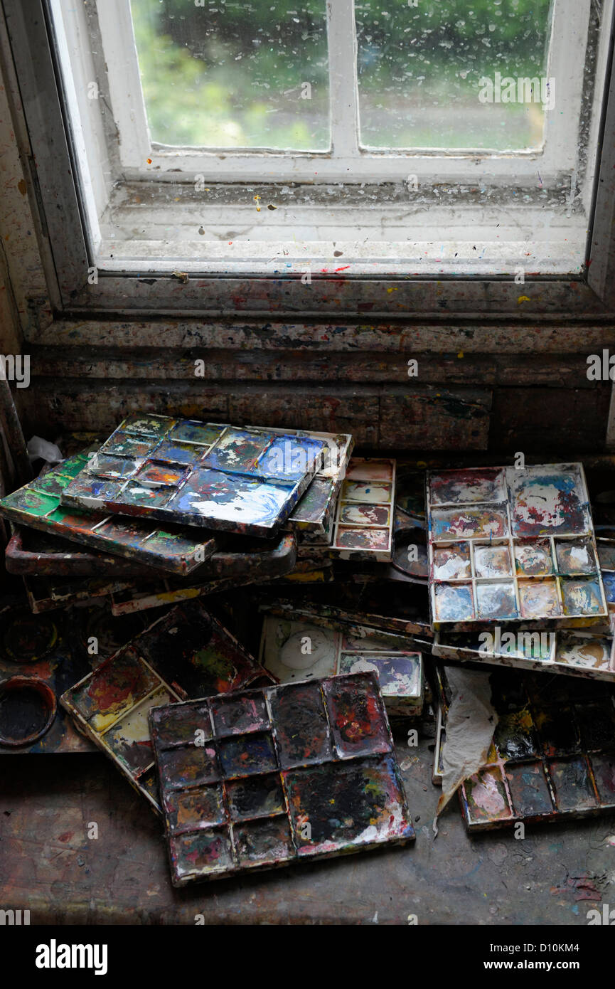 Discarded paint palettes by an old wooden window in an artists studio ...