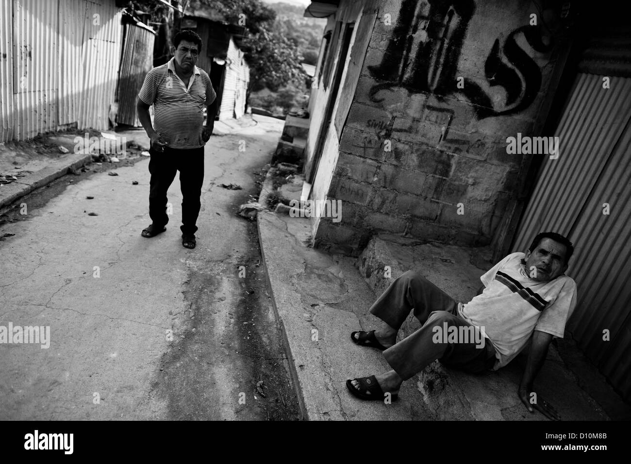 An old man sits in front of the gang graffiti painted on the wall in ...