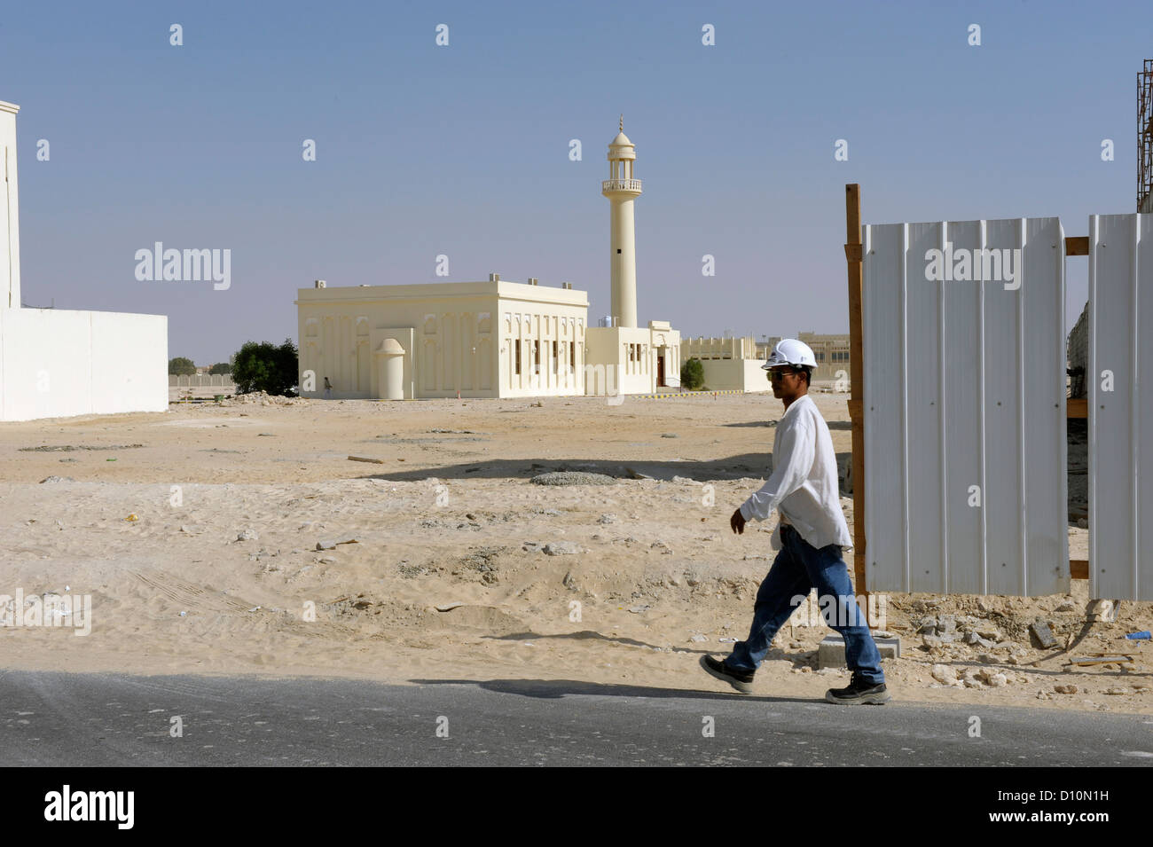 Indian construction worker passing building site for new mosque in Doha ...