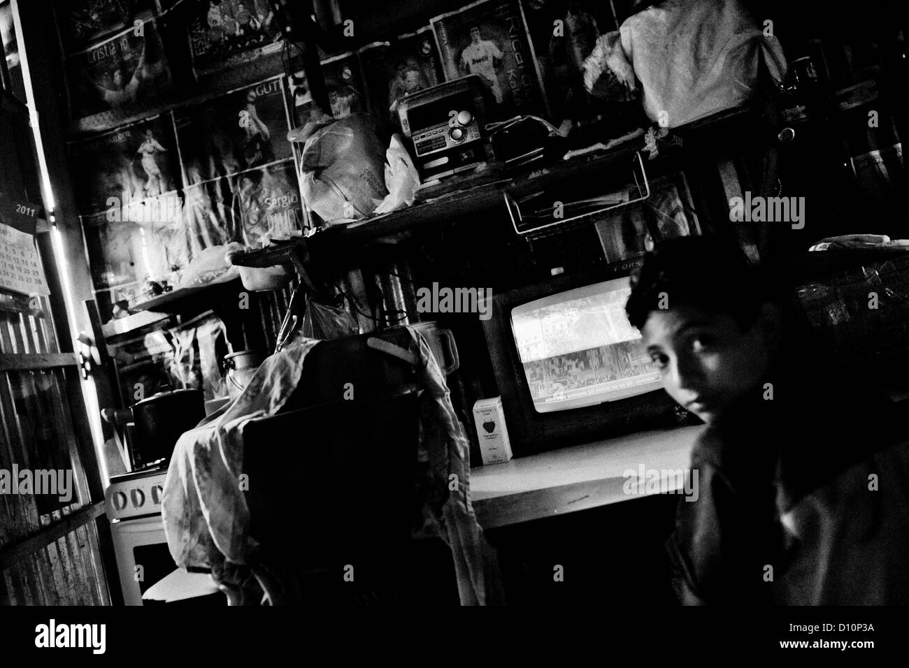 A young boy watches TV in a dark poor house located in the Mara ...