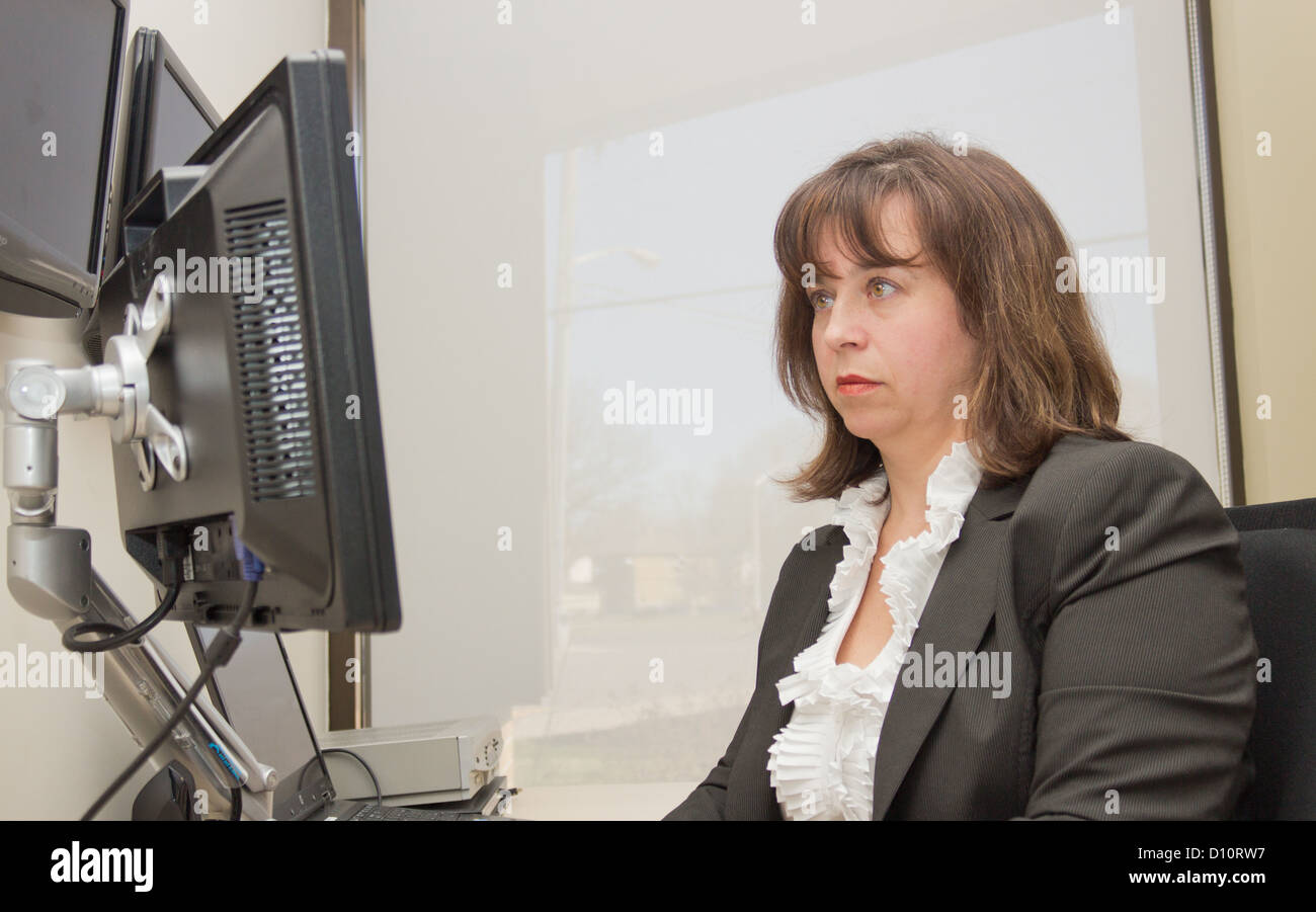 Business woman seated at desk looking at monitor Stock Photo - Alamy