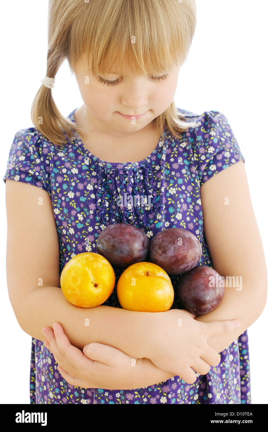 Calm girl looking at the plums in her crossed hands on the white ...