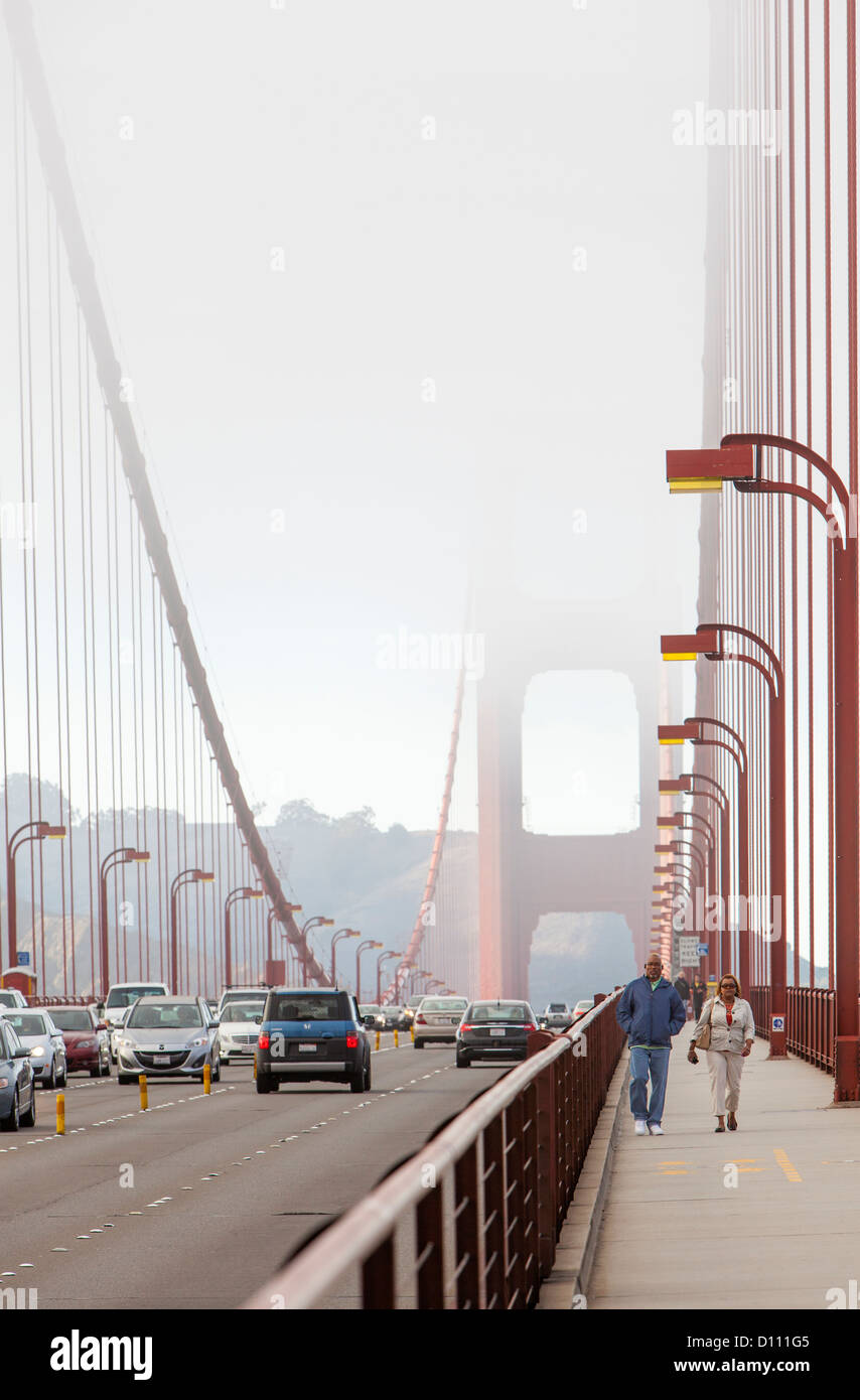 The San Francisco Golden Gate Bridge covered in fog and pedestrians ...