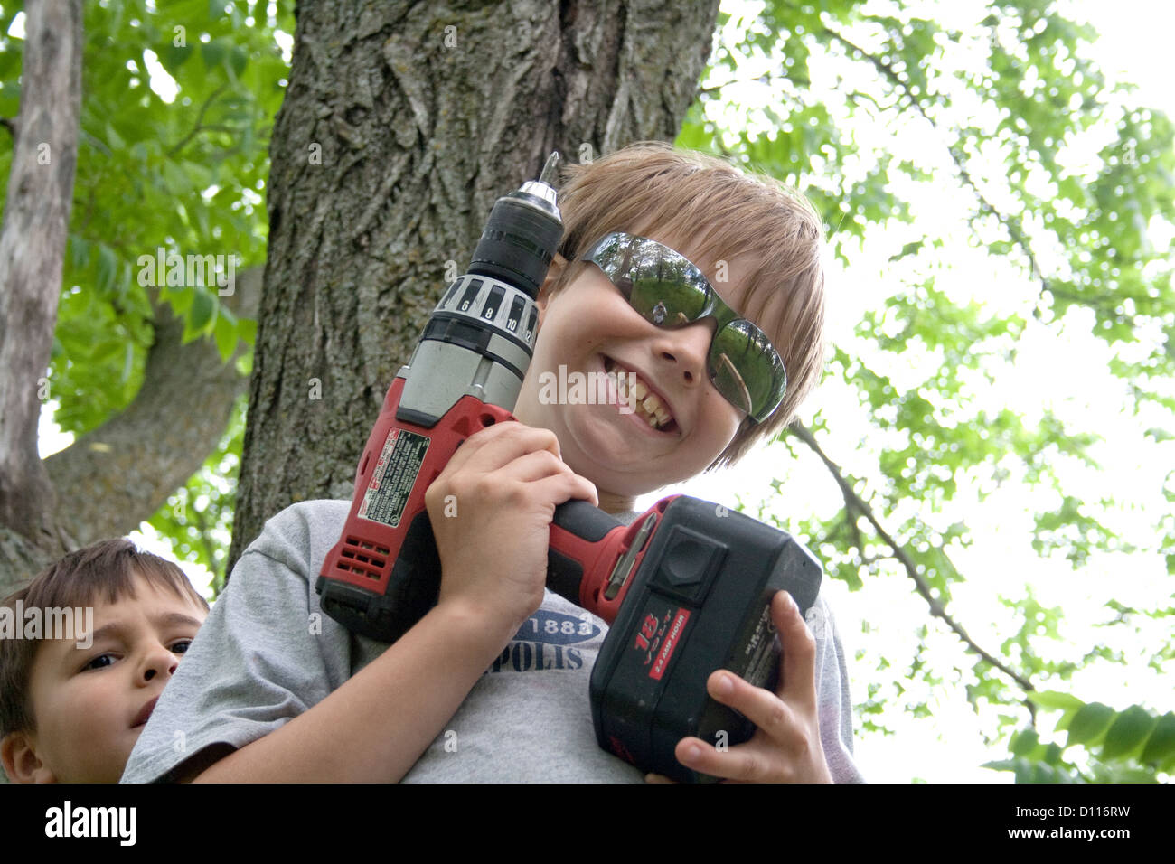 Boys age 7 and 10 with power screwdriver having fun building a tree ...