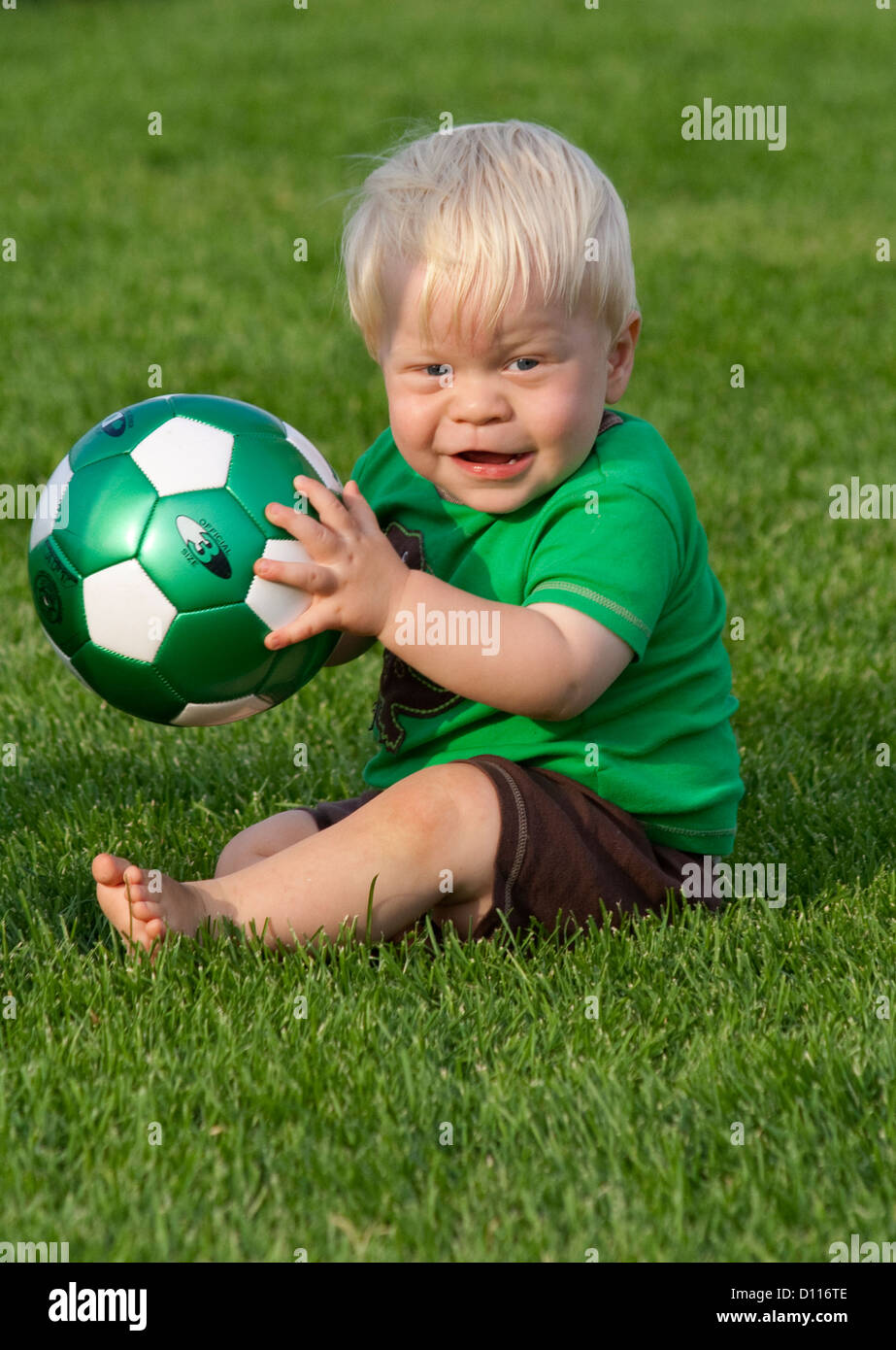 Rugged young toddler holding soccer ball on the field. Carondelet Field ...