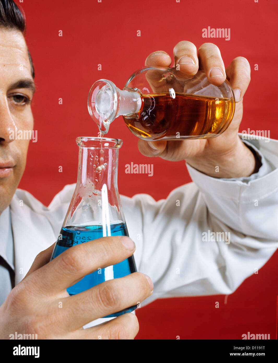 1970s LAB WORKER MAN POURING LIQUID FROM BOTTLE INTO FLASK Stock Photo ...