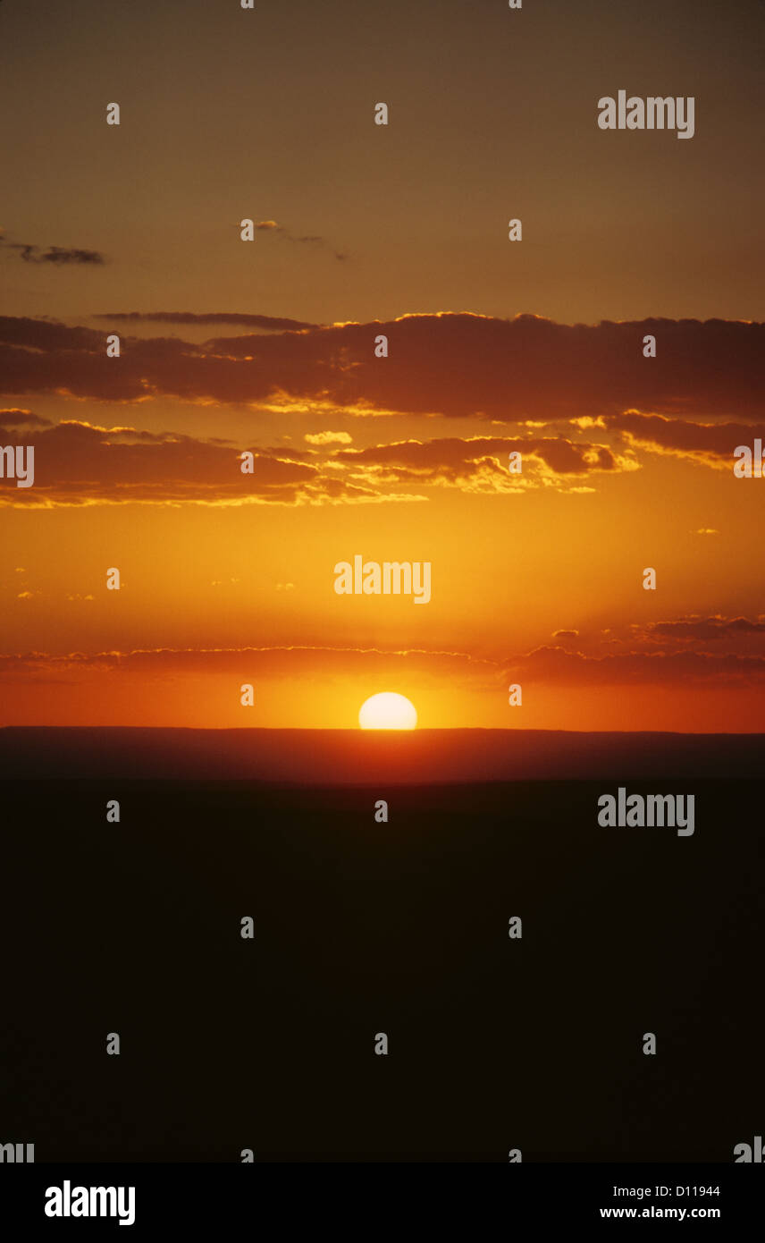 YELLOW SUN SETTING ON DARK HORIZON WITH CLOUDS IN GOLDEN SKY Stock ...