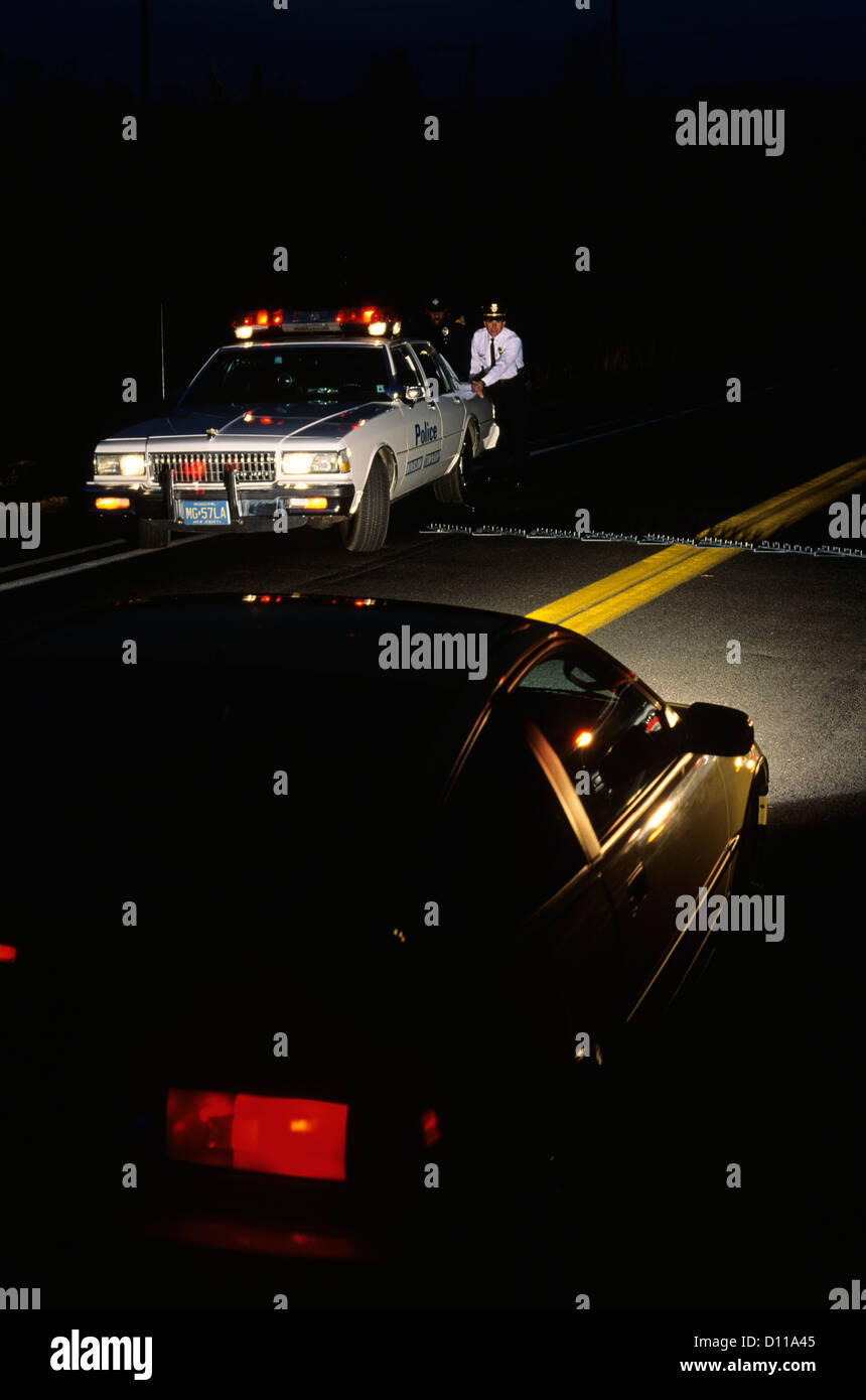 POLICE ROAD BLOCK TWO POLICE OFFICERS BEHIND PATROL CAR AND APPROACHING ...