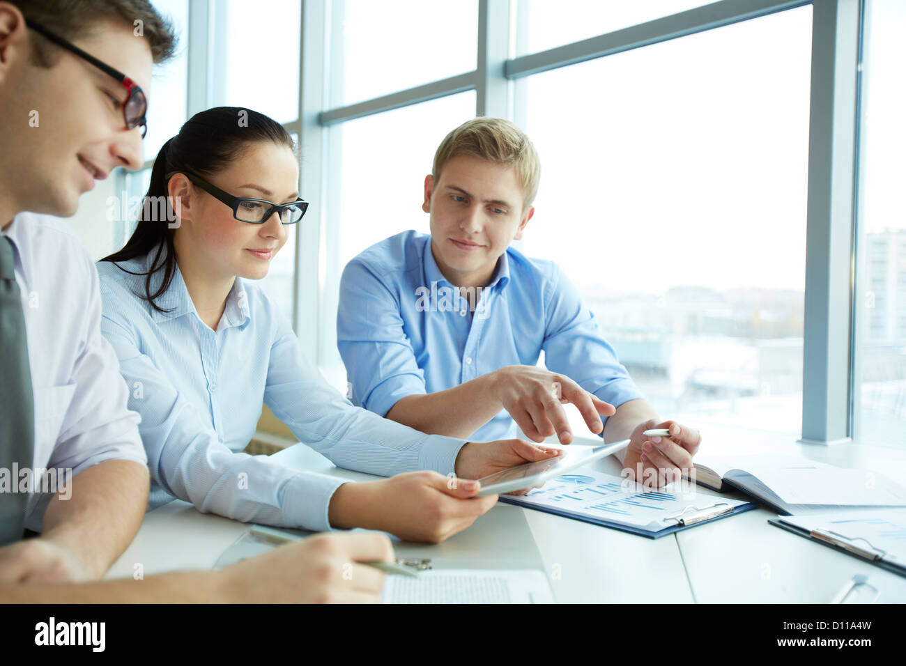 Image of three employees looking at touchscreen at meeting Stock Photo ...