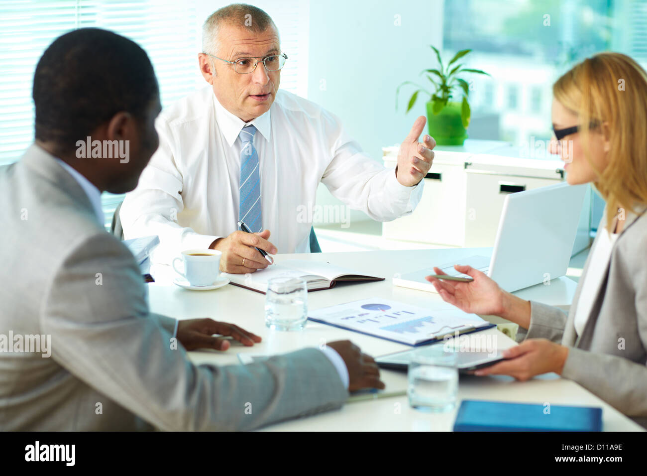 Portrait of senior boss talking and his employees at meeting Stock ...