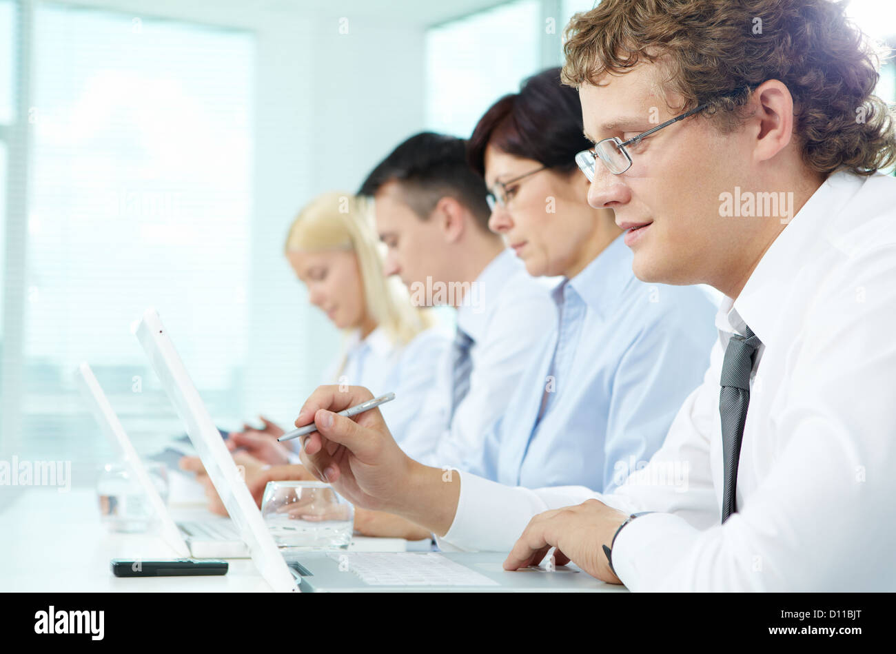 Business people sitting in a row and working Stock Photo - Alamy
