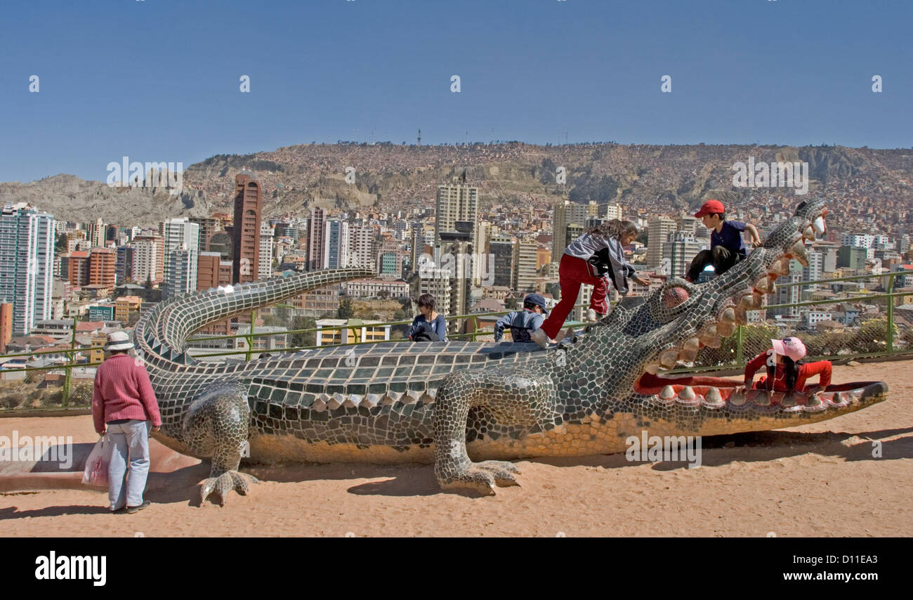 Children playing on crocodile statue in playground with view of city ...