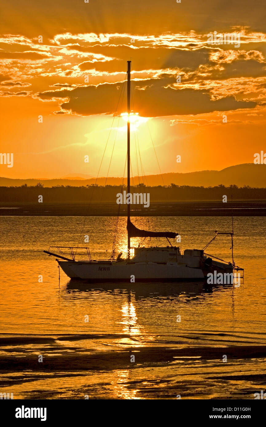 Sunset and boat with golden sky and water of Bustard Bay at coastal ...