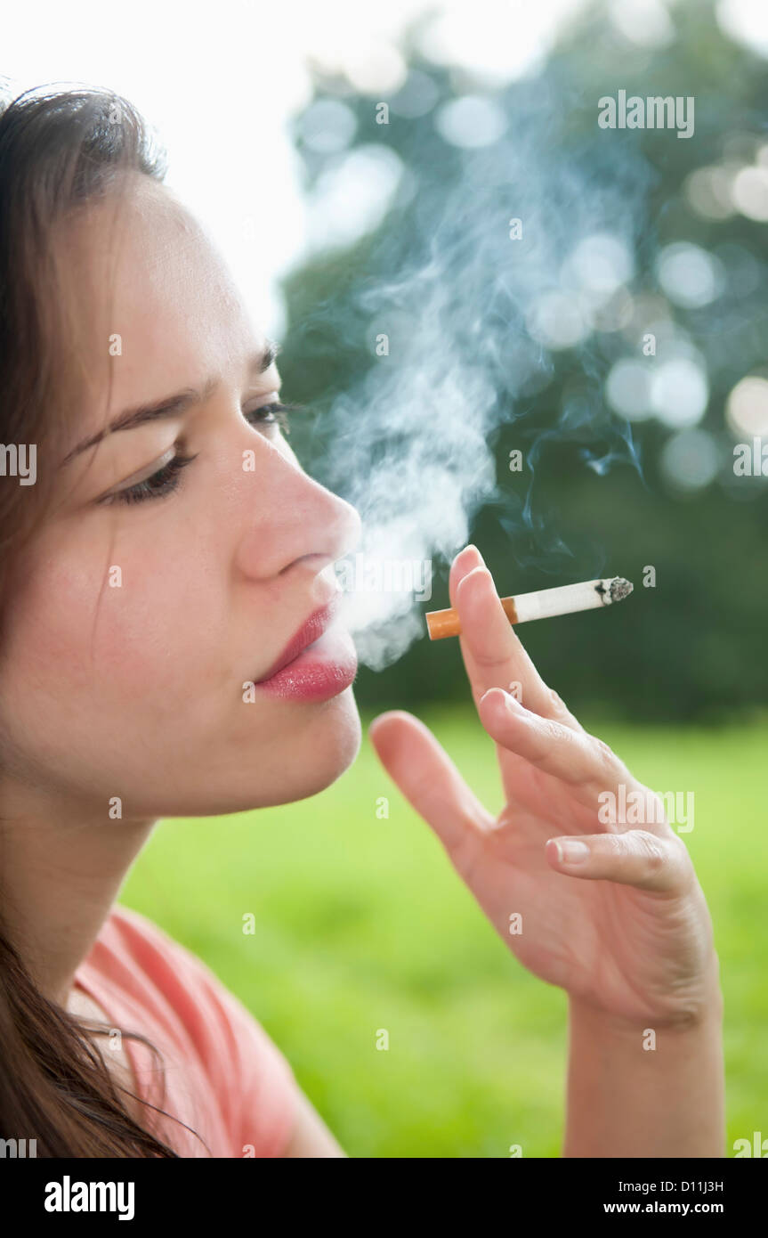 Germany, Berlin, Young woman smoking cigarette in park Stock Photo - Alamy