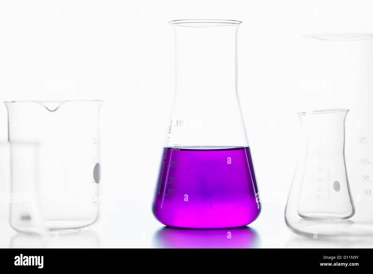 Volumetric flasks with pink solution against white background, close up ...