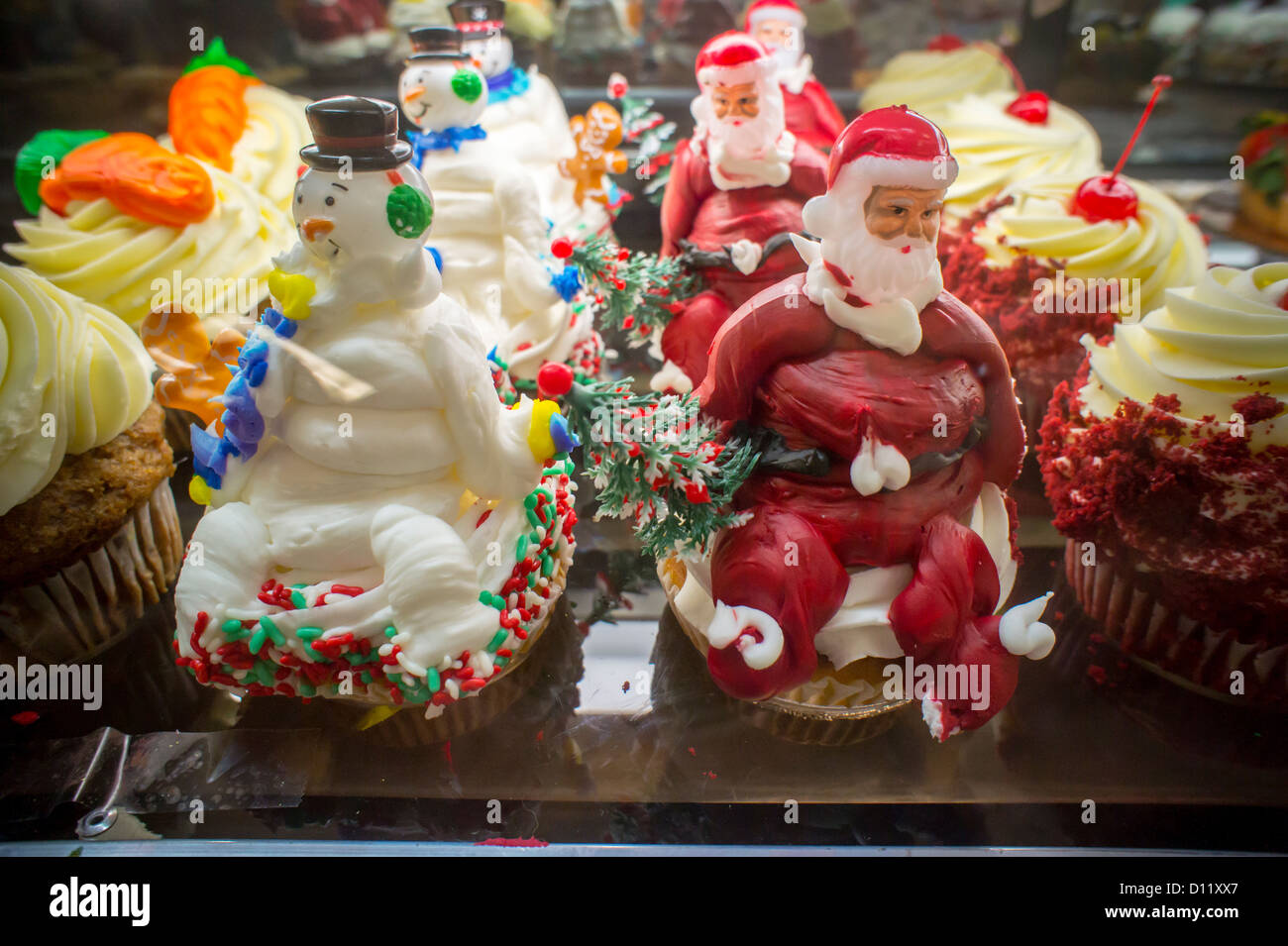 A selection of snowmen and Santa Claus cupcakes in a display case in a ...