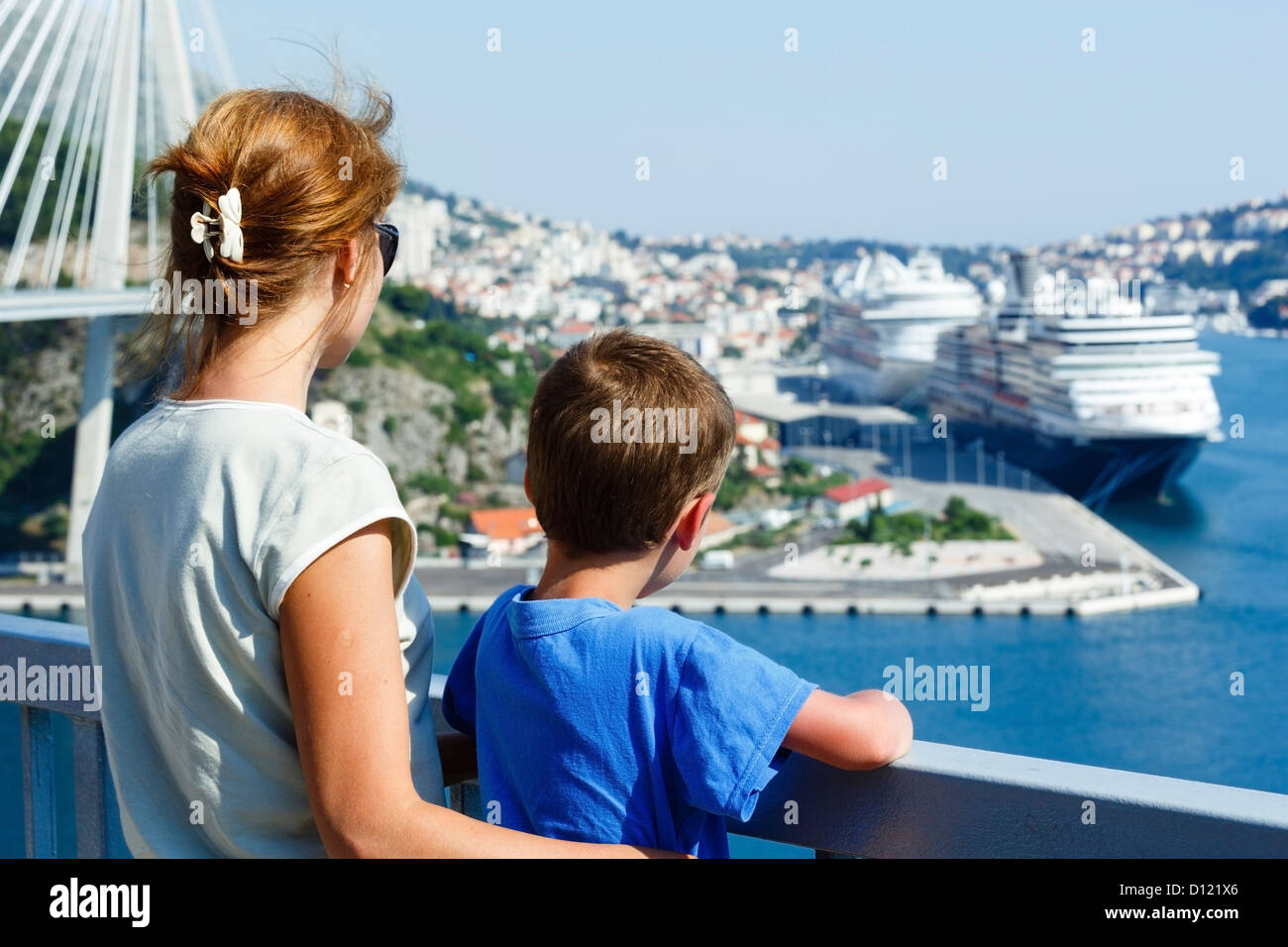Mother with child on bridge looking at the port with big liners ...