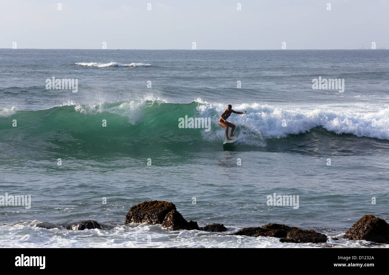 Traveling female surfer surfing over the reef at Marissa Bay on the ...
