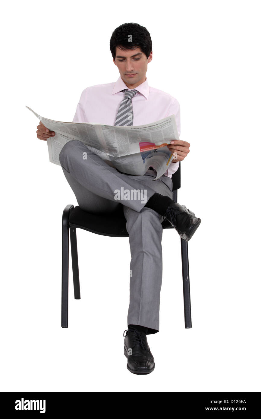 A businessman reading a newspaper on a chair Stock Photo - Alamy