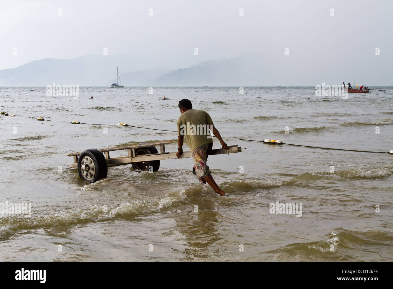 Man pushing a Cart into the Ocean to get Jetskis to the Beach on Patong ...