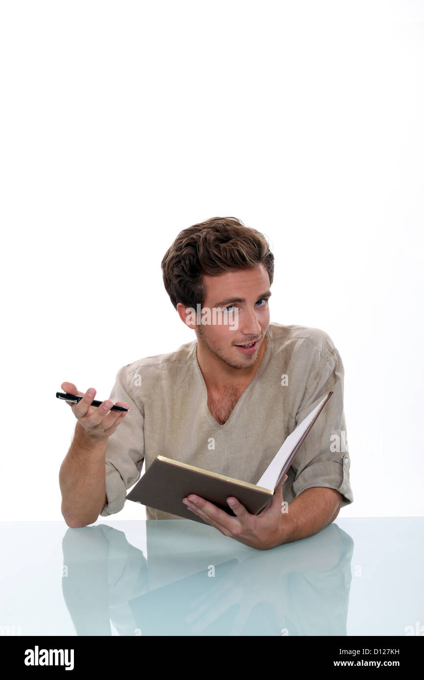 Young man writing in a book Stock Photo - Alamy