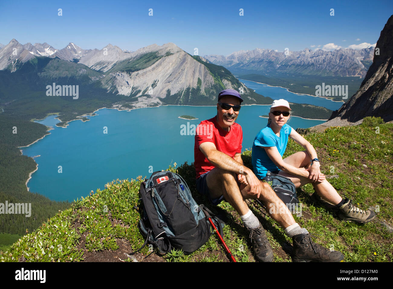 Male and female hiker sitting on top of a mountain ridge overlooking ...