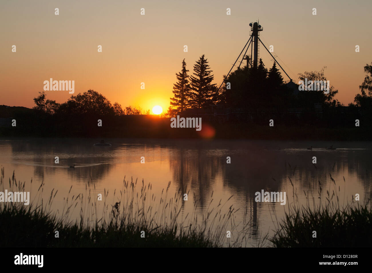 Silhouette Of A Reflecting Pond With Trees Grasses And Grain Bins With ...