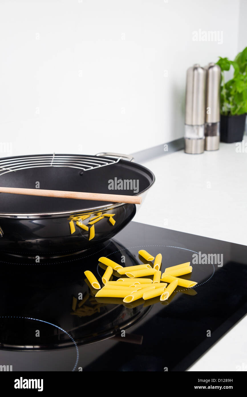 Frying pan, sticks and pasta in modern kitchen with induction stove ...