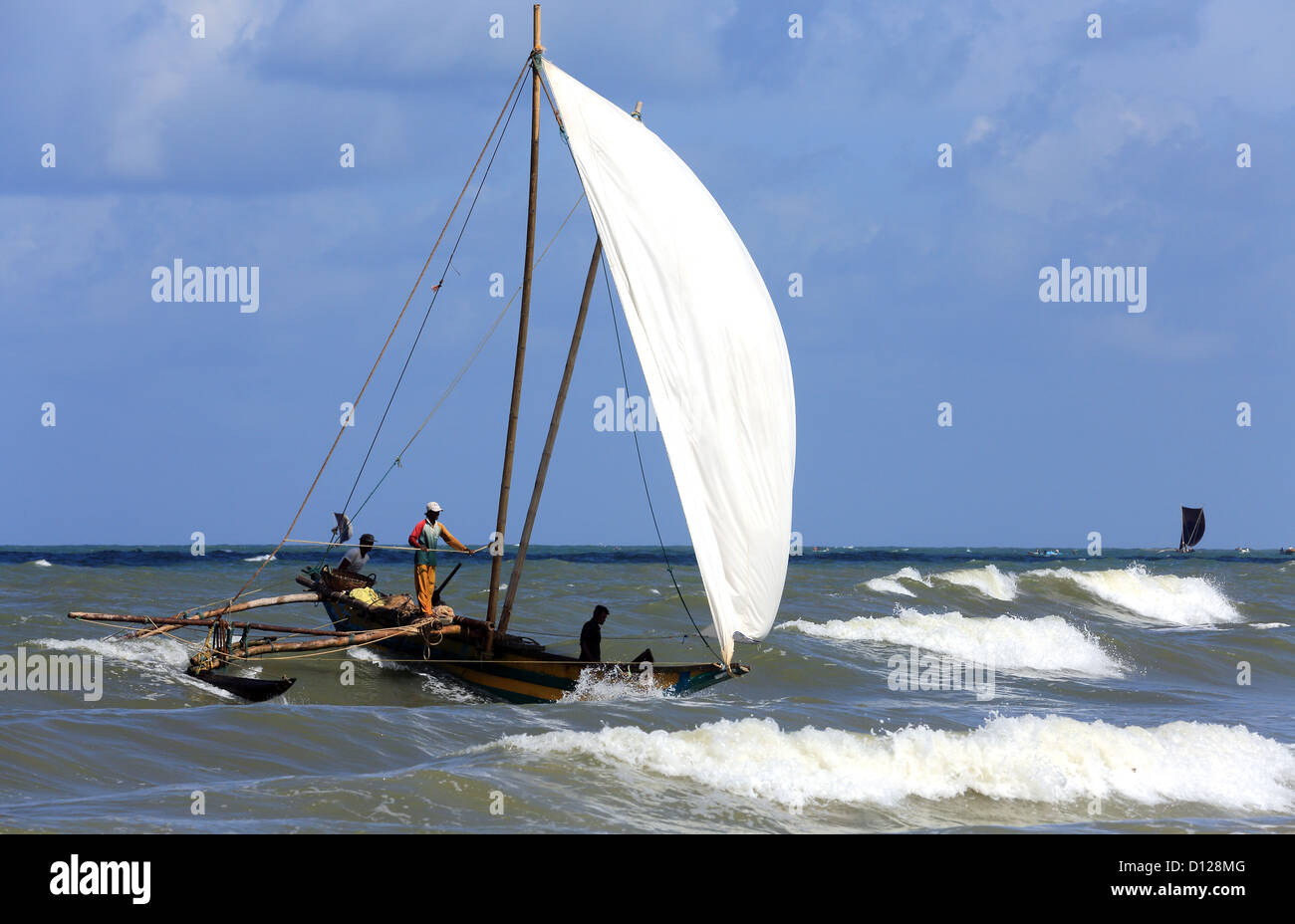 Fishermen sail a wooden outrigger sailing fishing boat through the surf ...