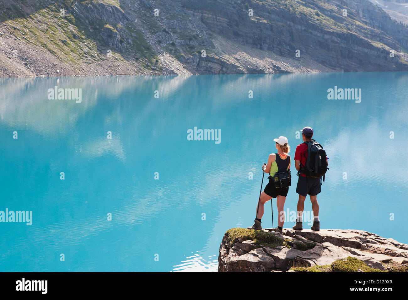 Female And Male Hikers On Rock Cliff Overlooking Mountain Lake; Field ...