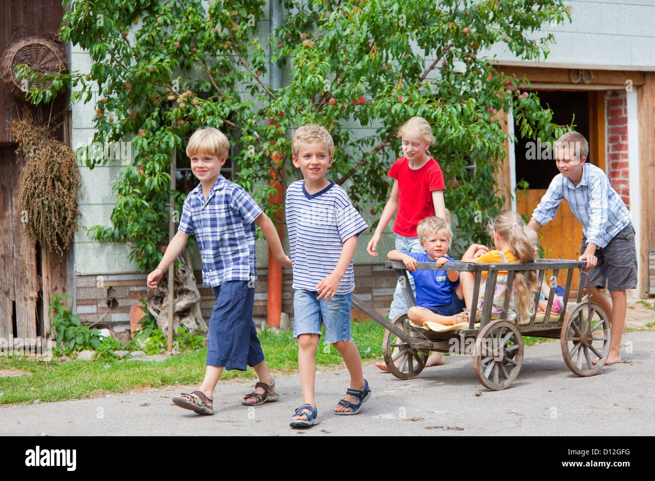 Germany, Bavaria, Group of children playing with hand cart in front of ...