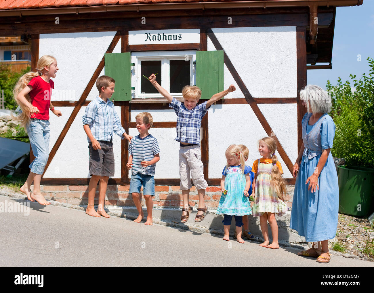 Germany, Bavaria, Woman with group of children playing in front of ...