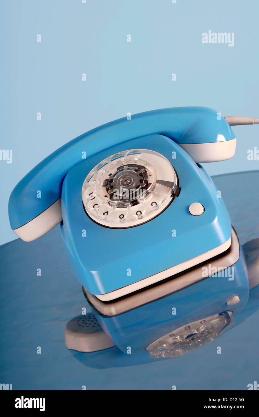 Old fashioned blue telephone reflecting on glass table, close up Stock ...