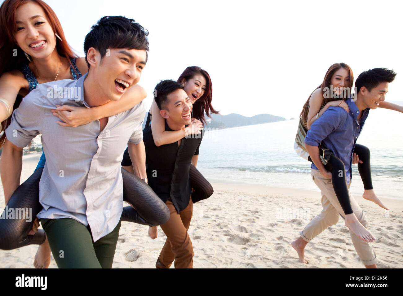 Excited young people playing piggyback on the beach of Repulse Bay ...