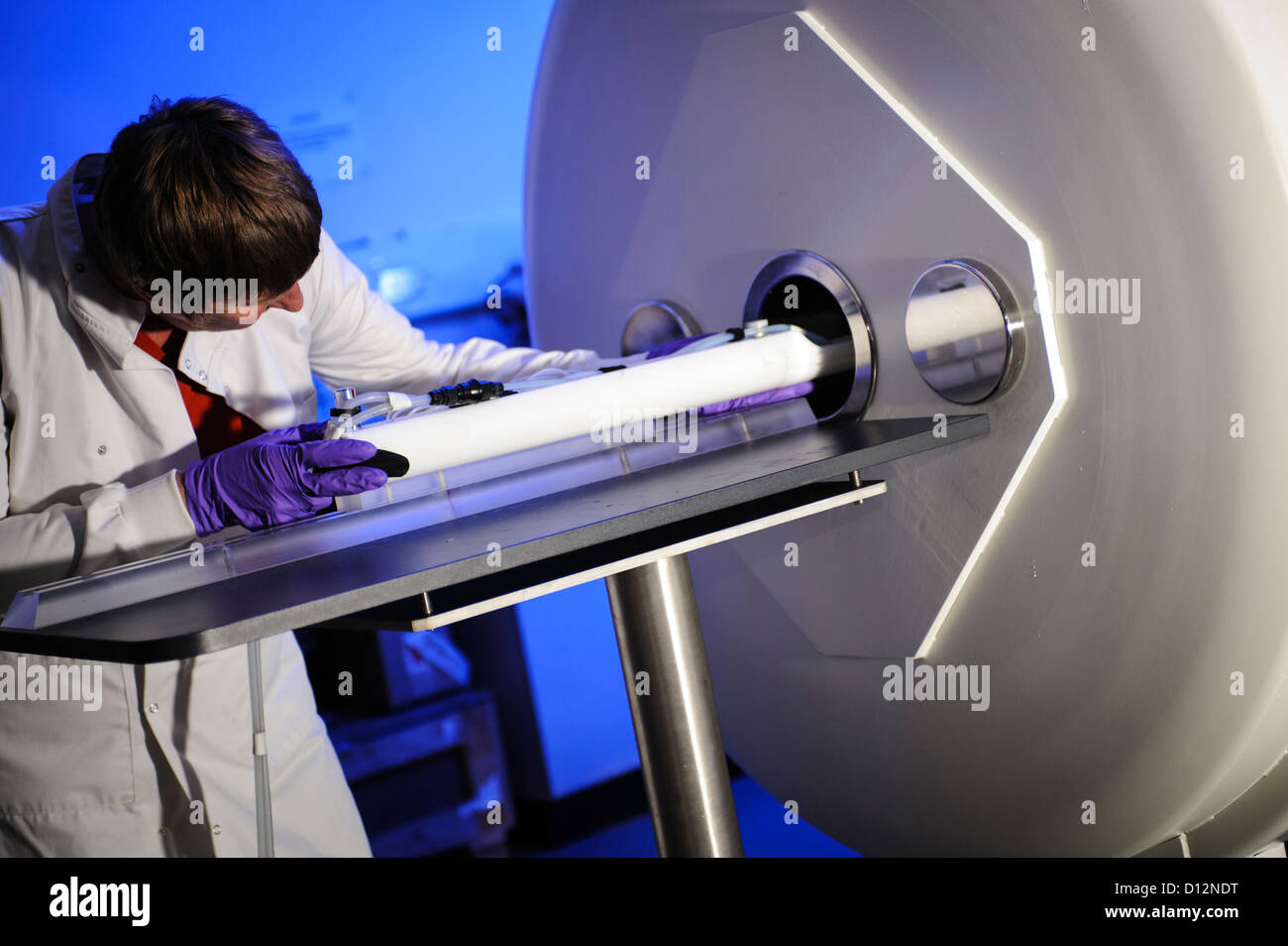 Scientist or technician loads a specimen on a tray into a small bore ...