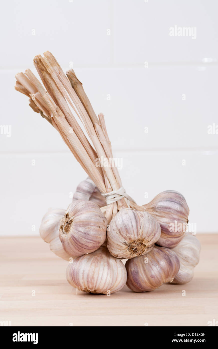 Bunch of tied garlic on wooden kitchen work surface Stock Photo - Alamy
