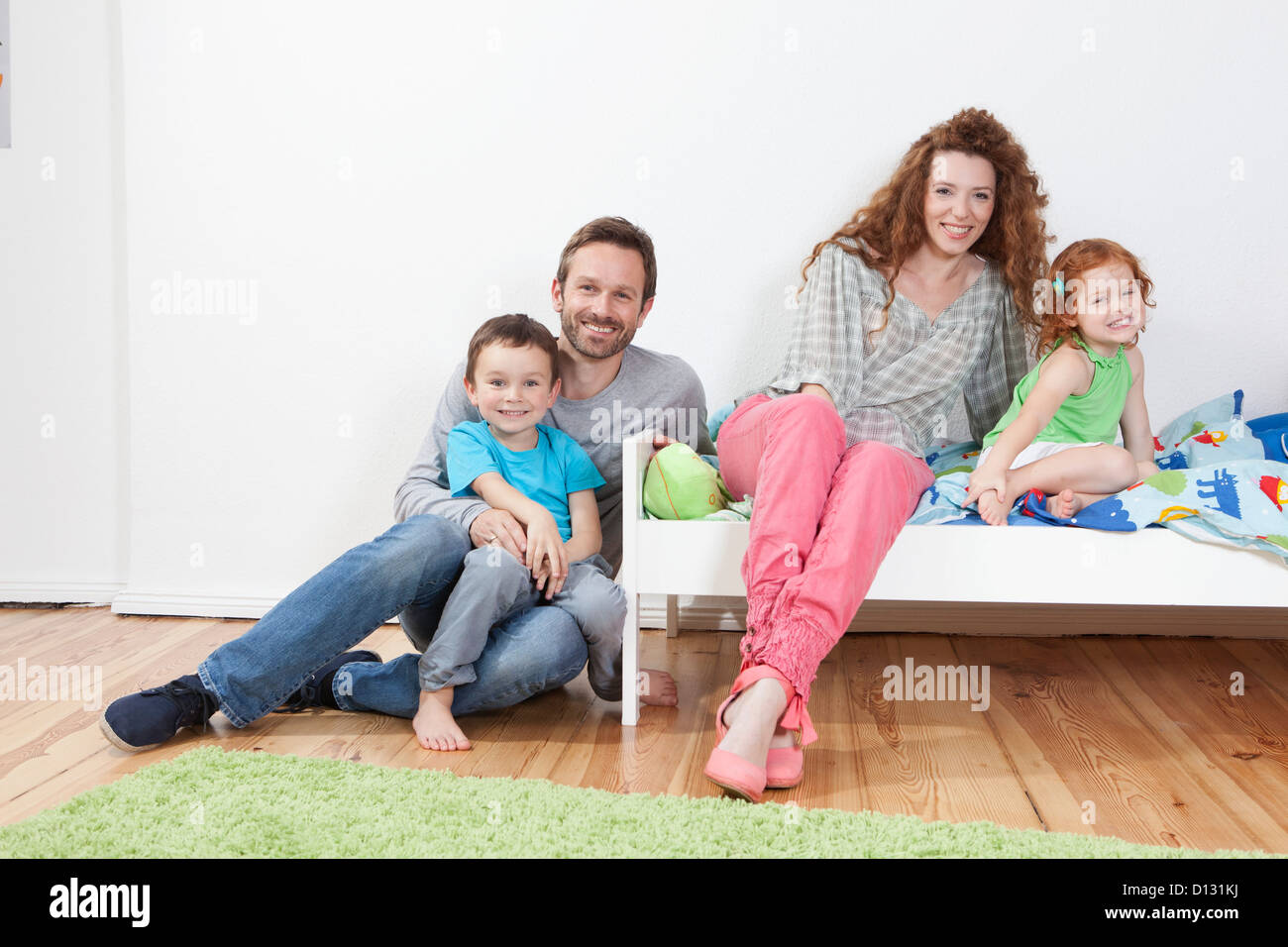 Germany, Berlin, Family sitting on bed, smiling, portrait Stock Photo ...