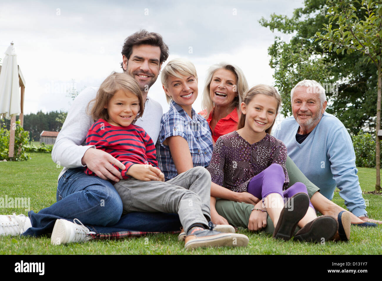 Germany, Bavaria, Nuremberg, Family sitting in grass, smiling, portrait ...