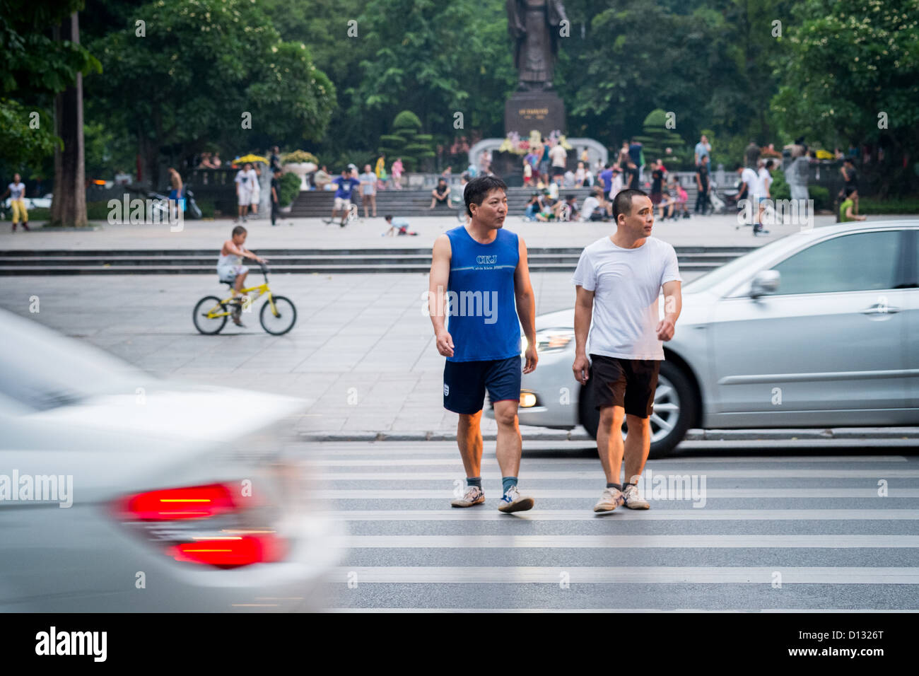 Two males walking across a zebra crossing in Hanoi Vietnam South East ...