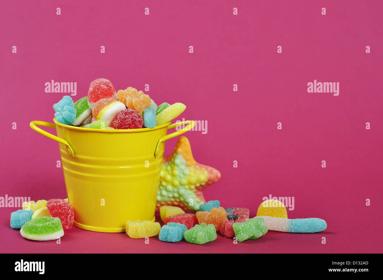Colorful candies in yellow bucket on pink background Stock Photo - Alamy